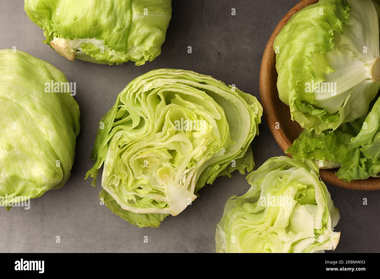 Fresh green cut and whole iceberg lettuce heads on grey table, flat lay ...