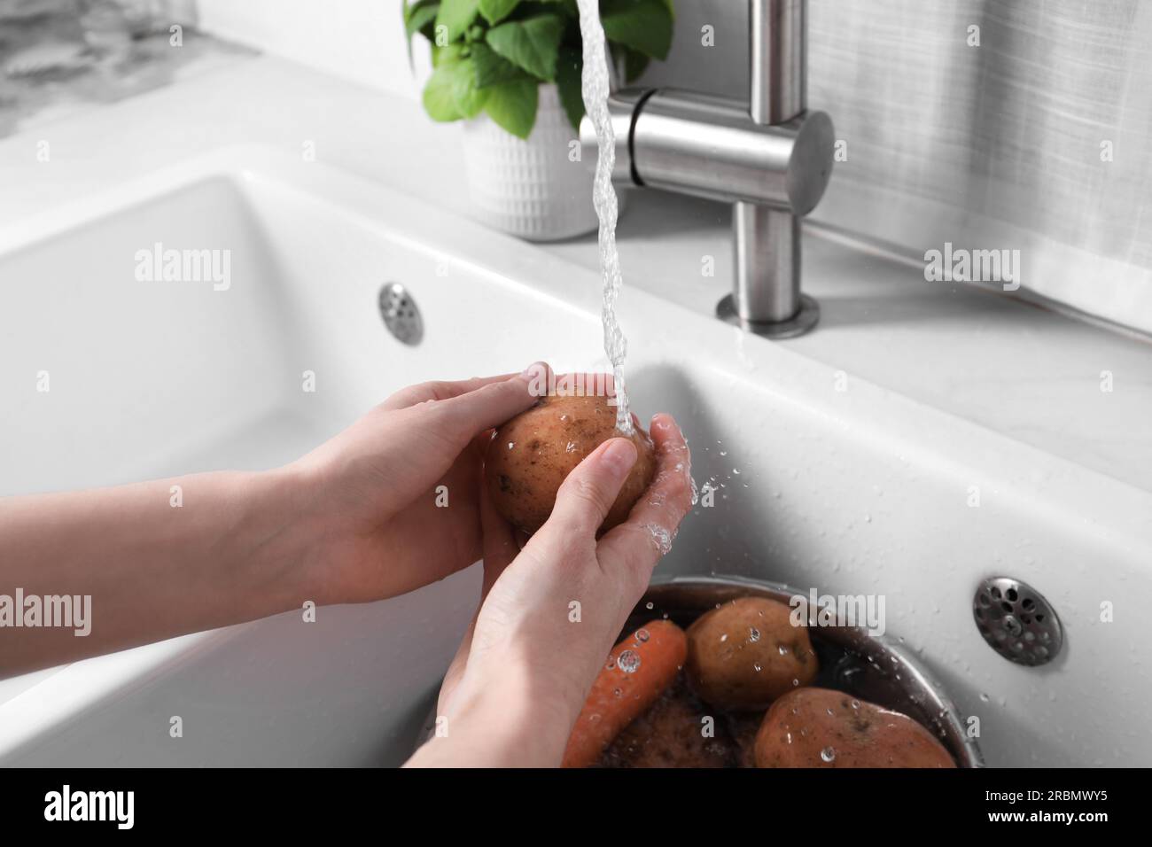 Woman washing fresh potato in kitchen sink, closeup. Cooking ...