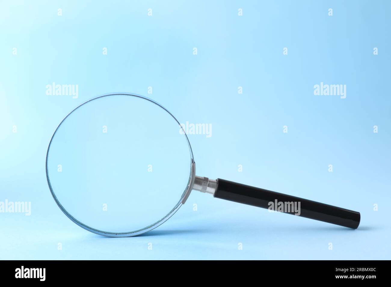 Magnifying glass with handle on light blue background Stock Photo - Alamy