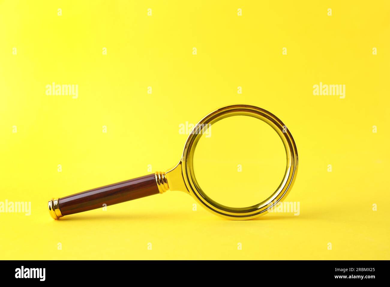 Magnifying glass with handle on yellow background Stock Photo - Alamy