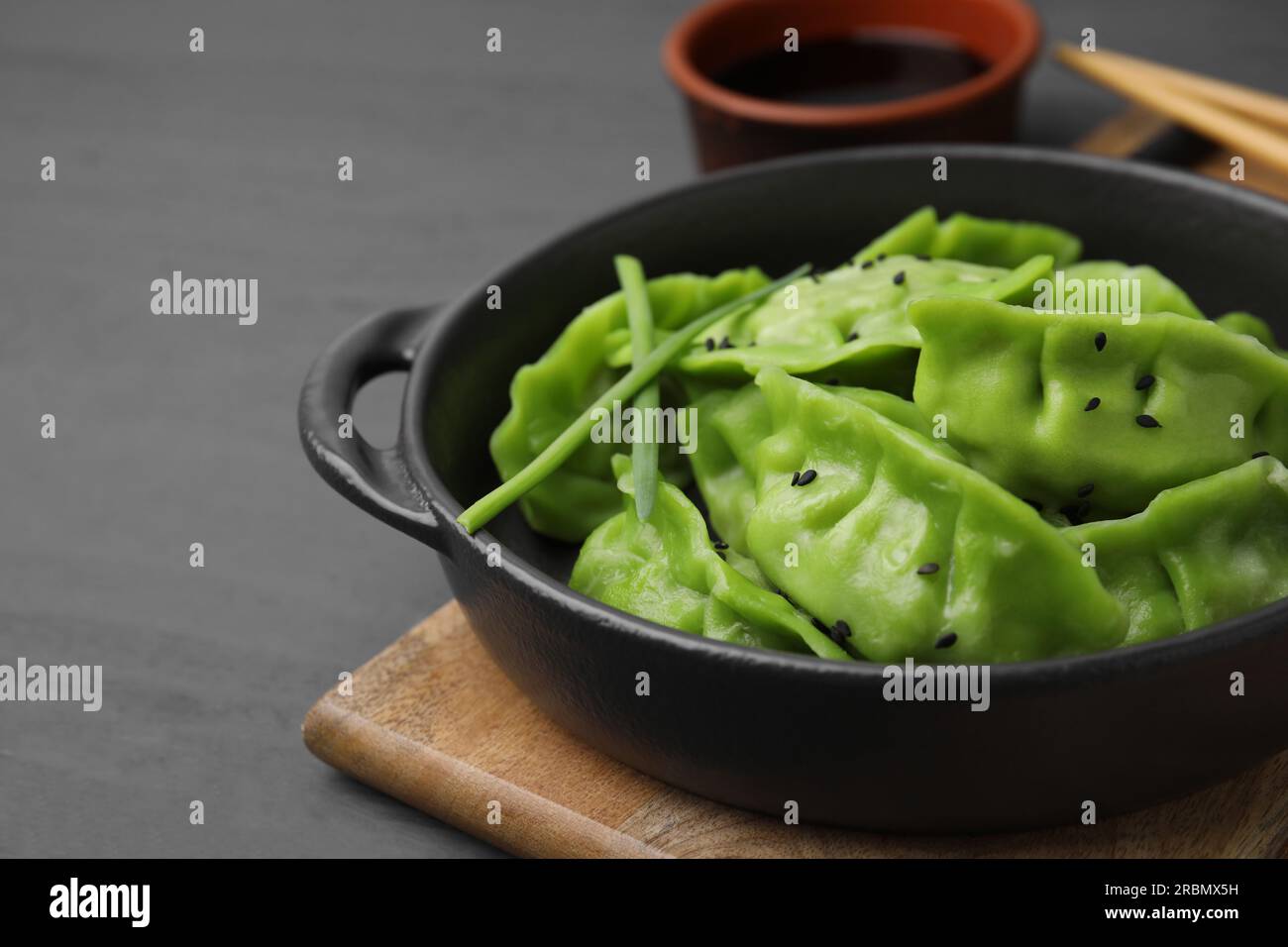 Delicious green dumplings (gyozas) and soy sauce on grey wooden table ...