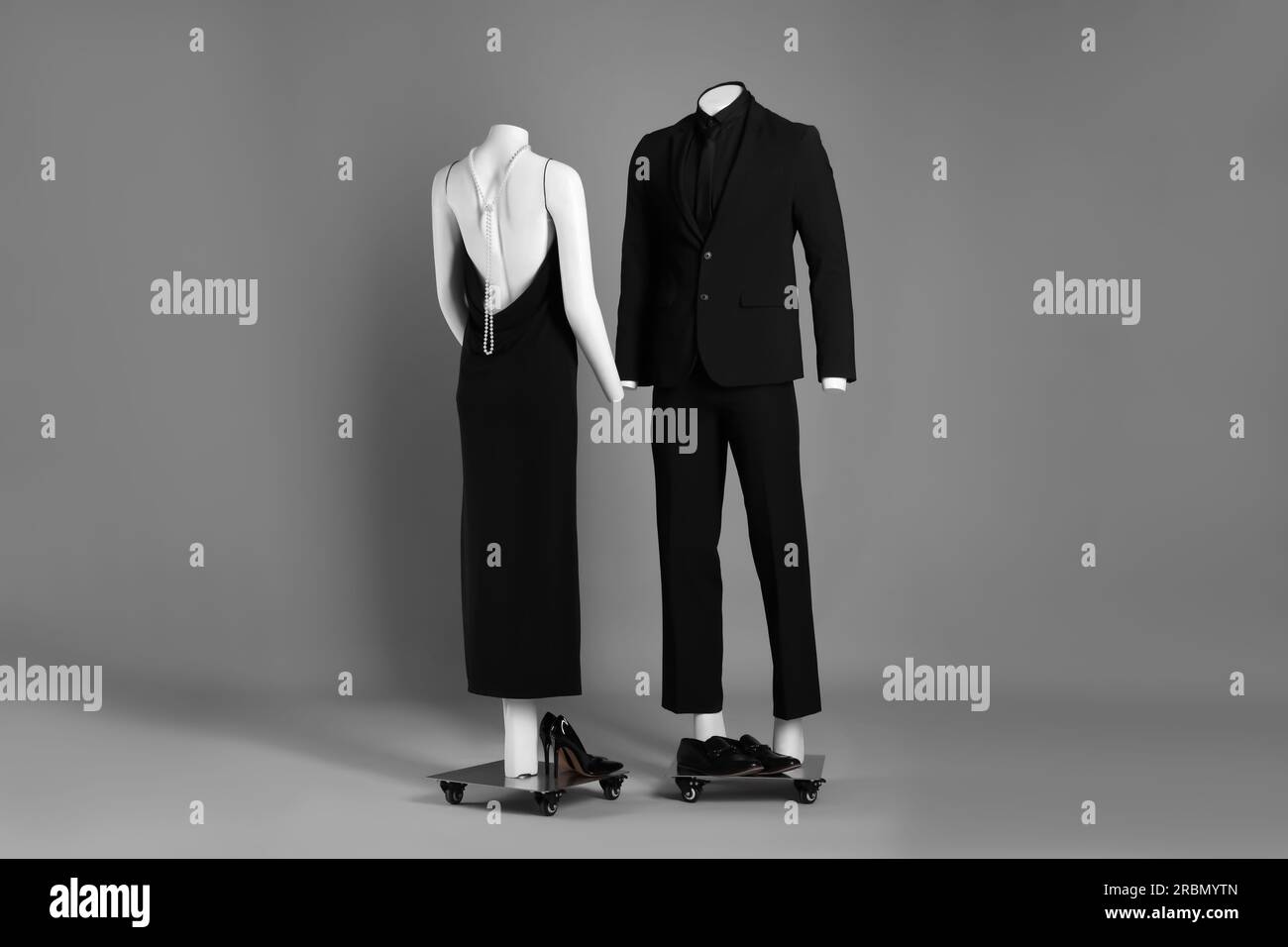 Male and female mannequins dressed in elegant outfits on grey ...