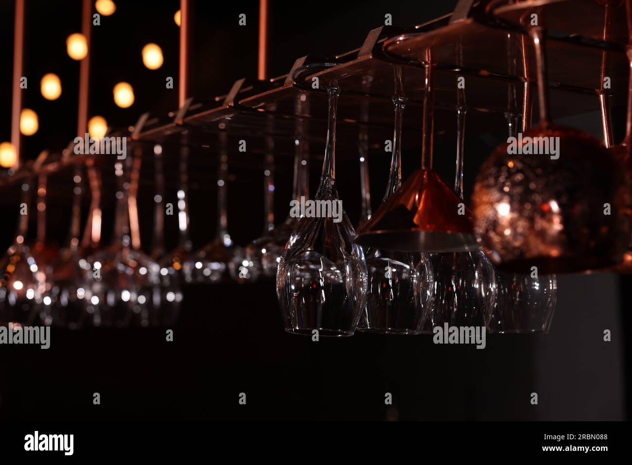 Different glassware hanging on bar counter, closeup Stock Photo - Alamy