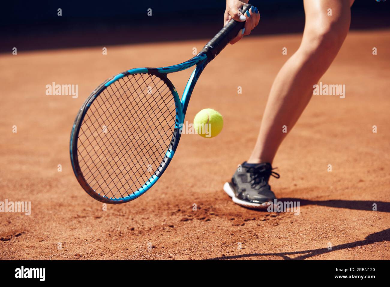 Cropped image of female legs in sportswear and tennis racket with ball ...