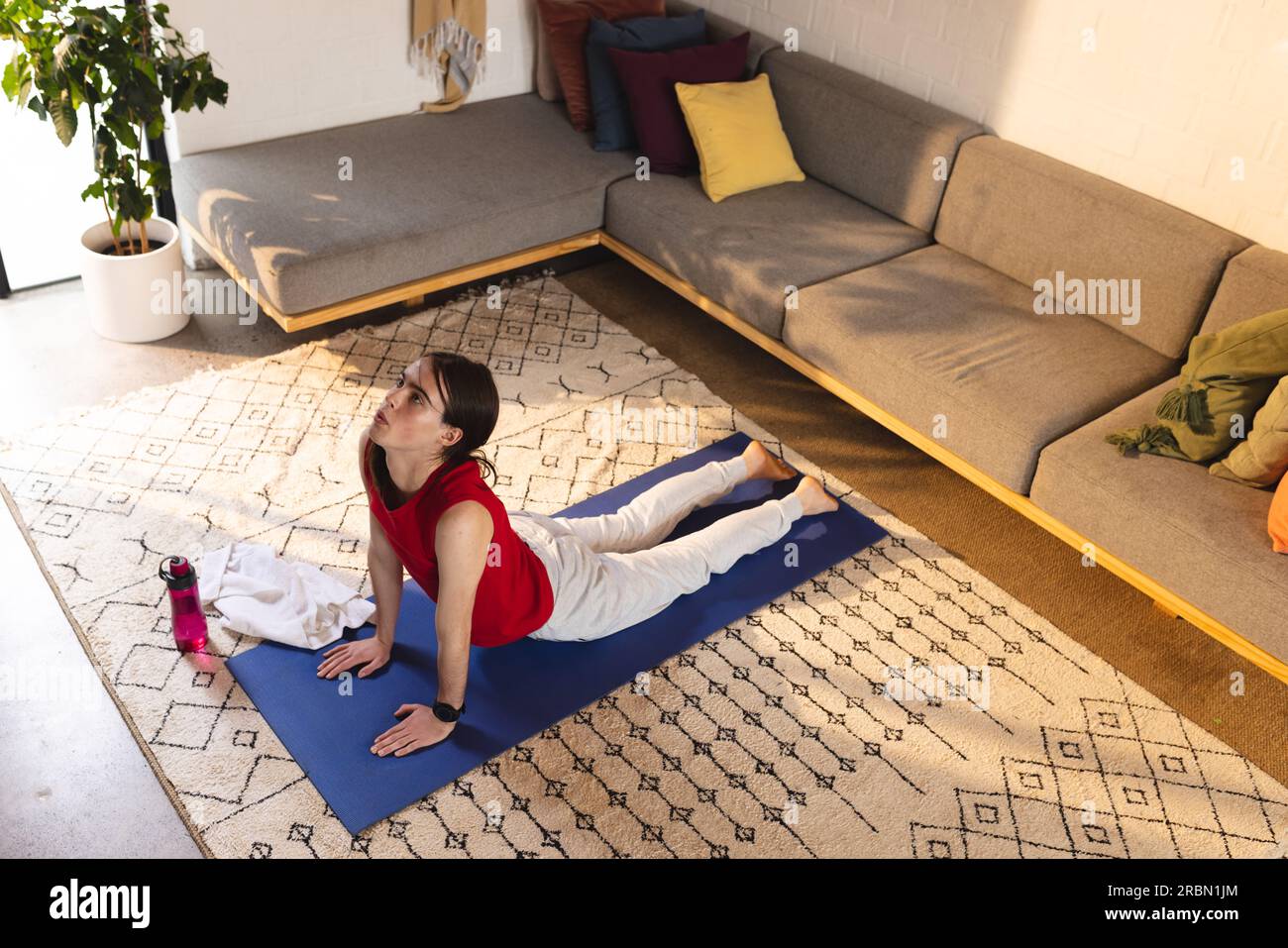 Non-binary transgender woman practicing yoga, stretching on yoga mat at ...