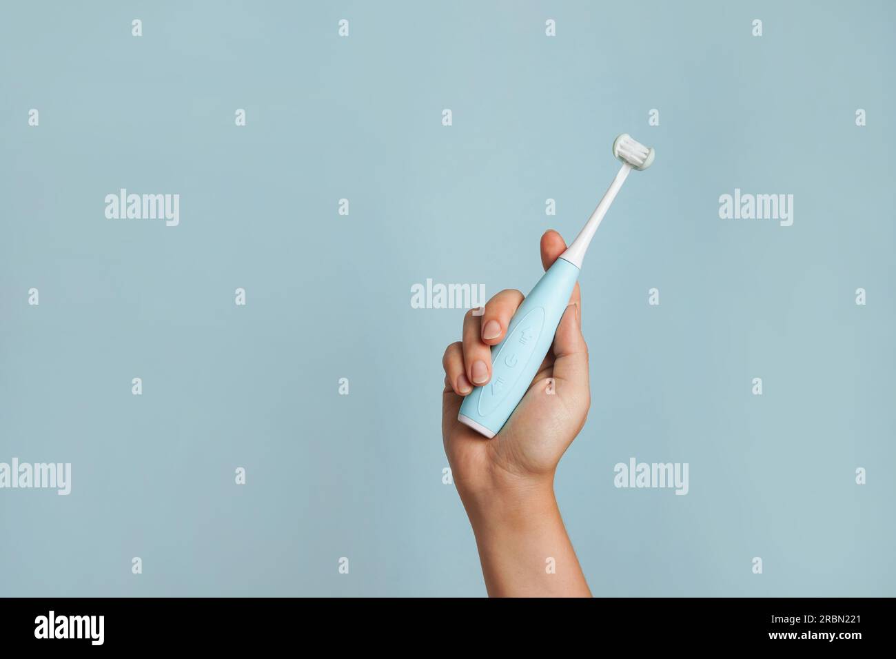 Smart electric toothbrush in female hand on blue background. Modern ...