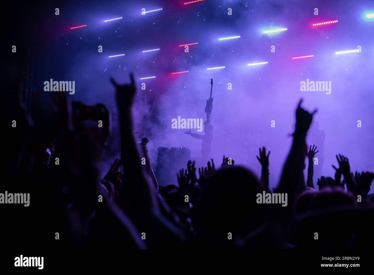 A group of people enjoy an illuminated music festival with raised arms ...