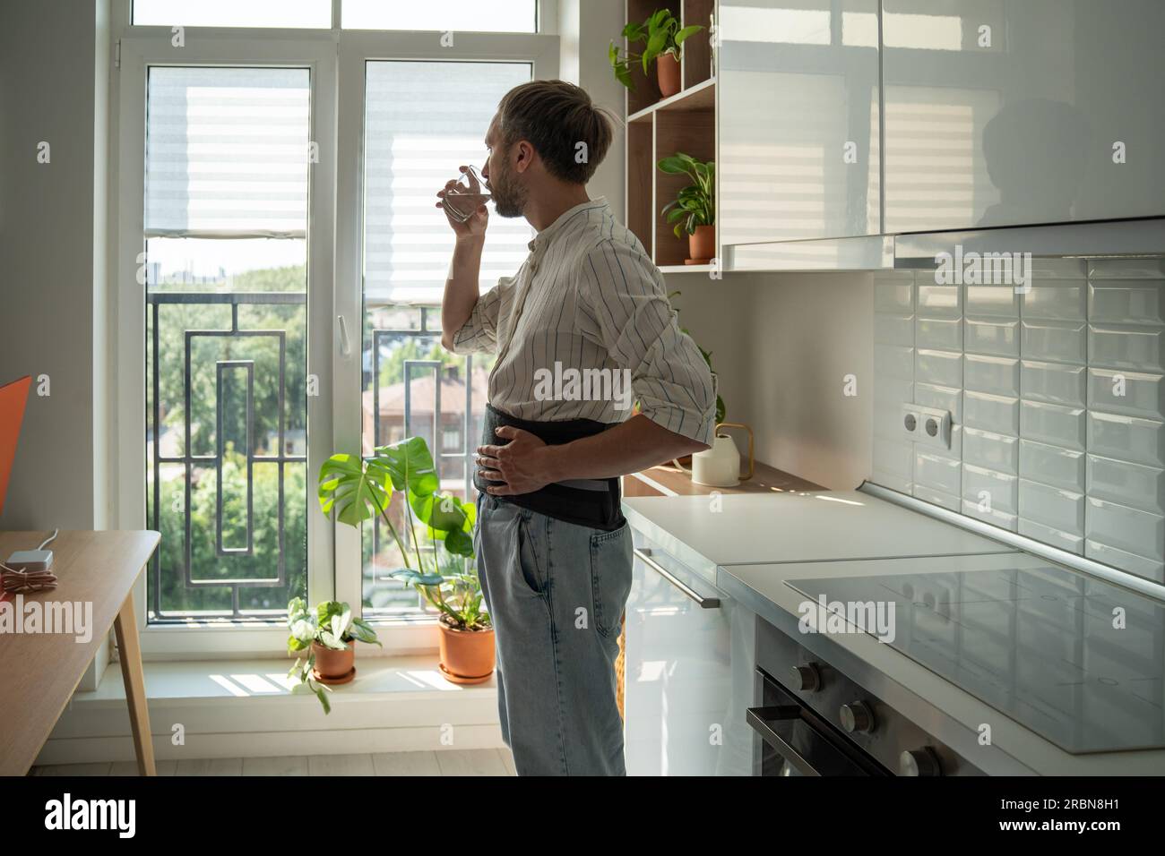 Young man wearing spinal brace drinking water recovering from back ...