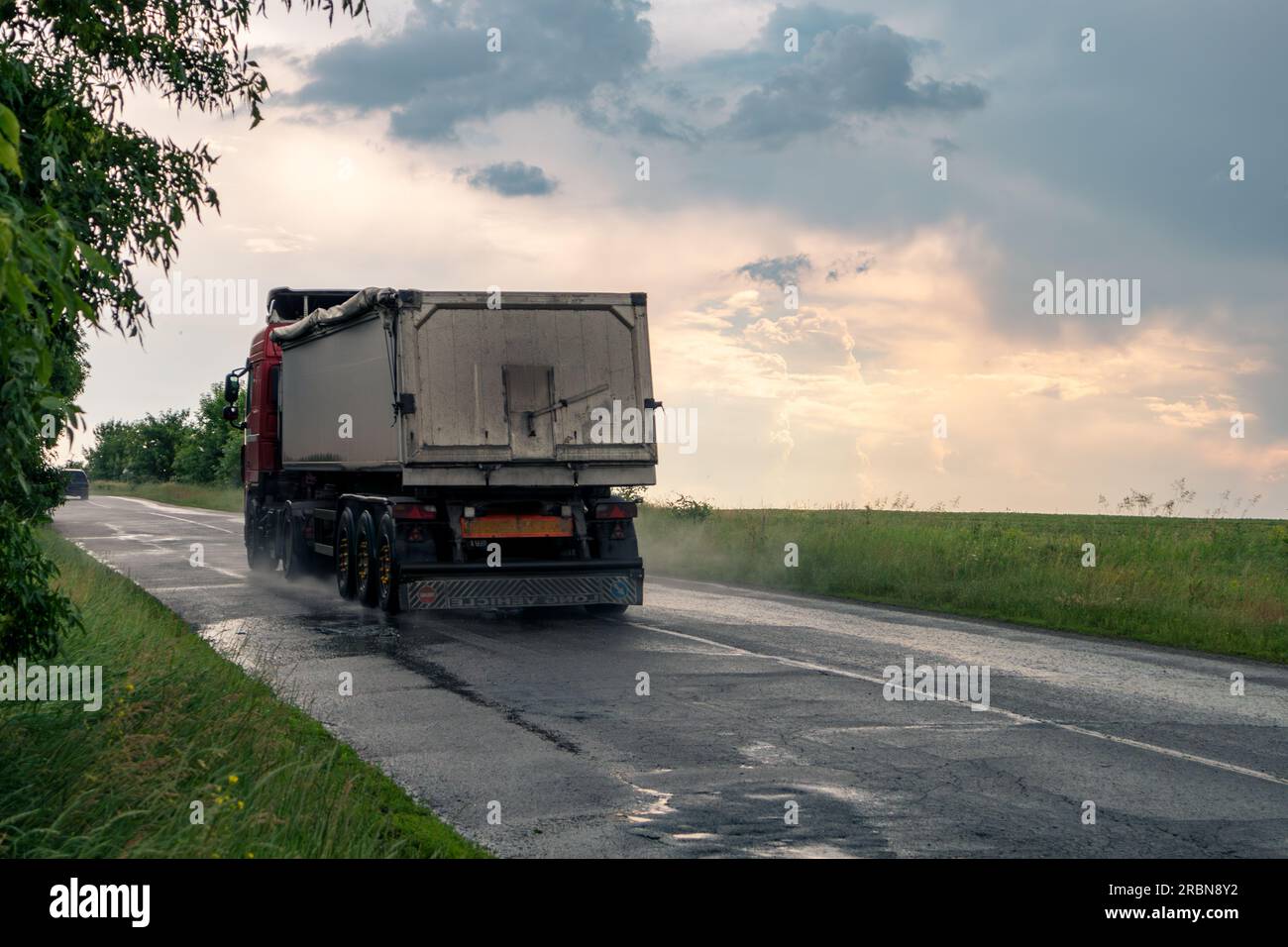 Heavy truck vehicle driving wet rural asphalt road in rainy weather ...