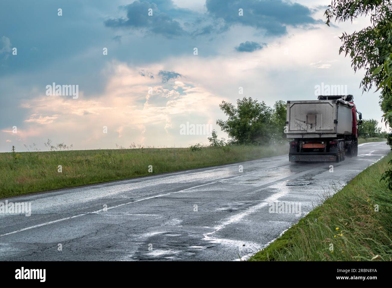 Heavy truck vehicle driving wet asphalt road driveway in stormy rainy ...