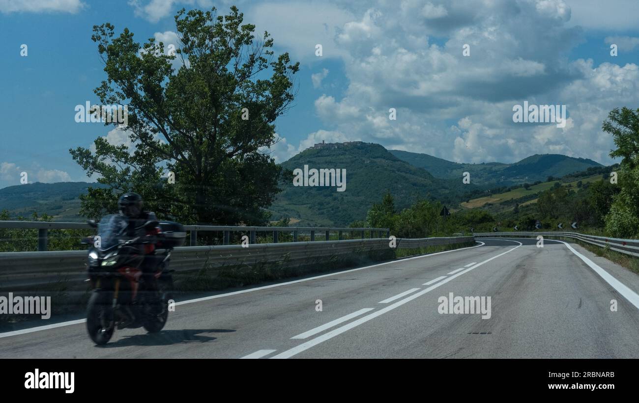 Motorbike riding away from the town on the hill Stock Photo - Alamy