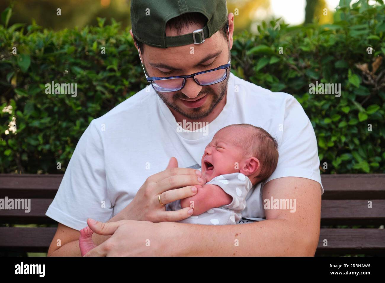 Young father consoling his crying newborn baby in a park Stock Photo ...