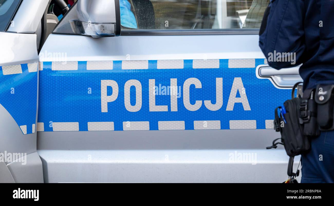 Blue Polish police vehicle and a policeman, policja, police car side ...