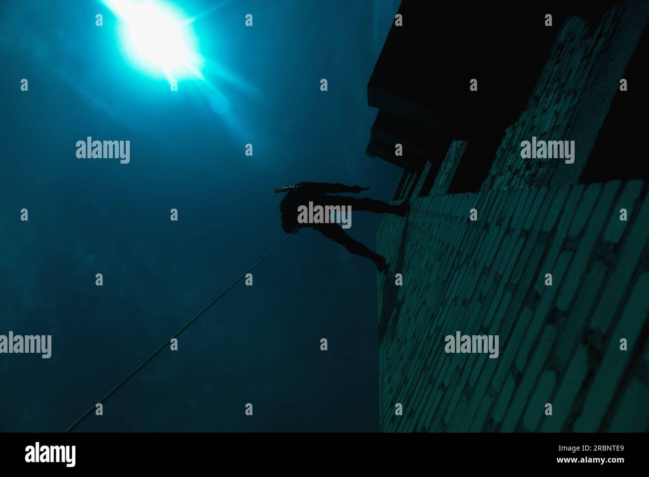 Silhouette of police officer in tactical gear descending from a height ...