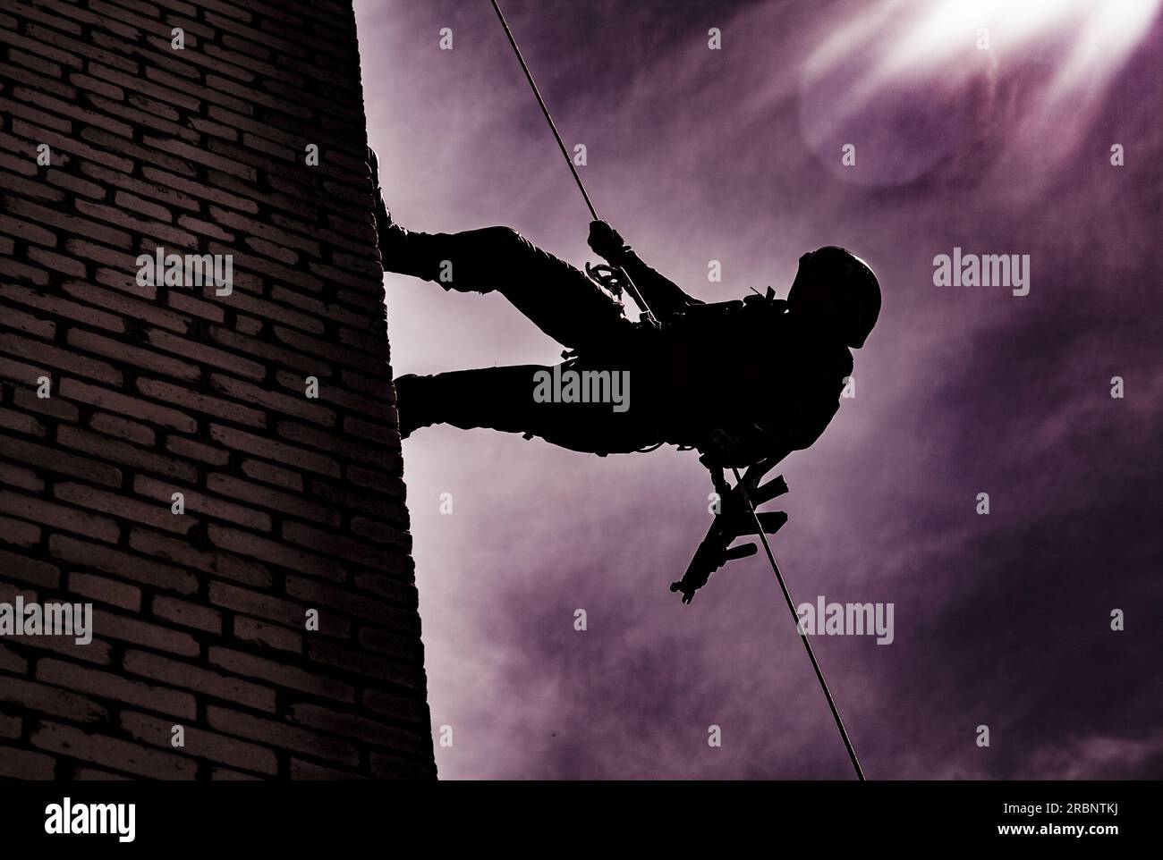 Silhouette of police officer in tactical gear descending from a height ...