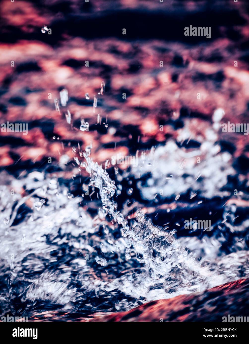 Close up of clear water splash around red coloured waters - conceptual ...