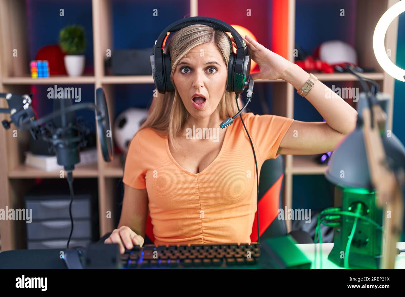 Young woman playing video games crazy and scared with hands on head ...