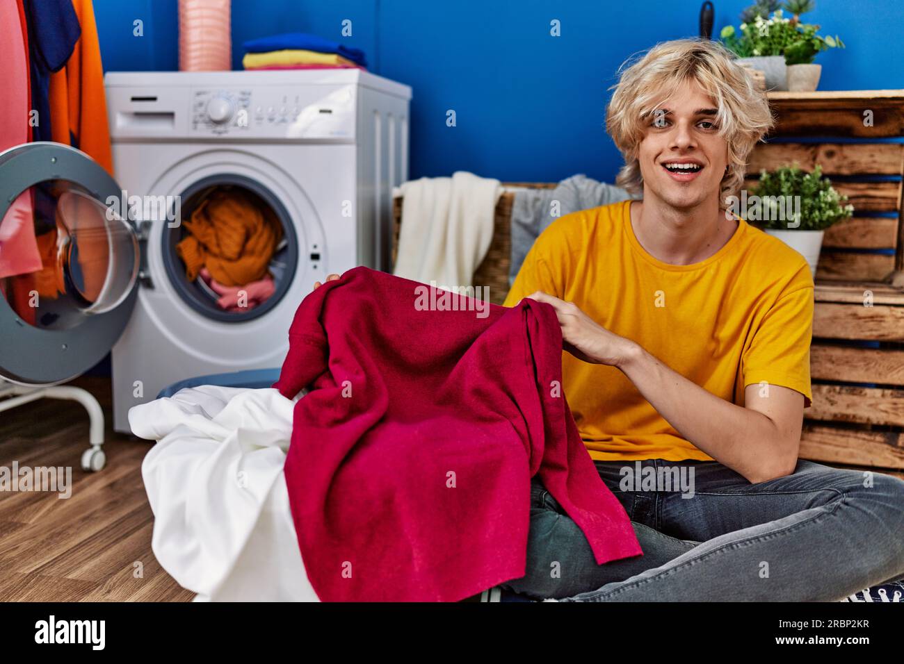Young blond man smiling confident washing clothes at laundry room Stock ...