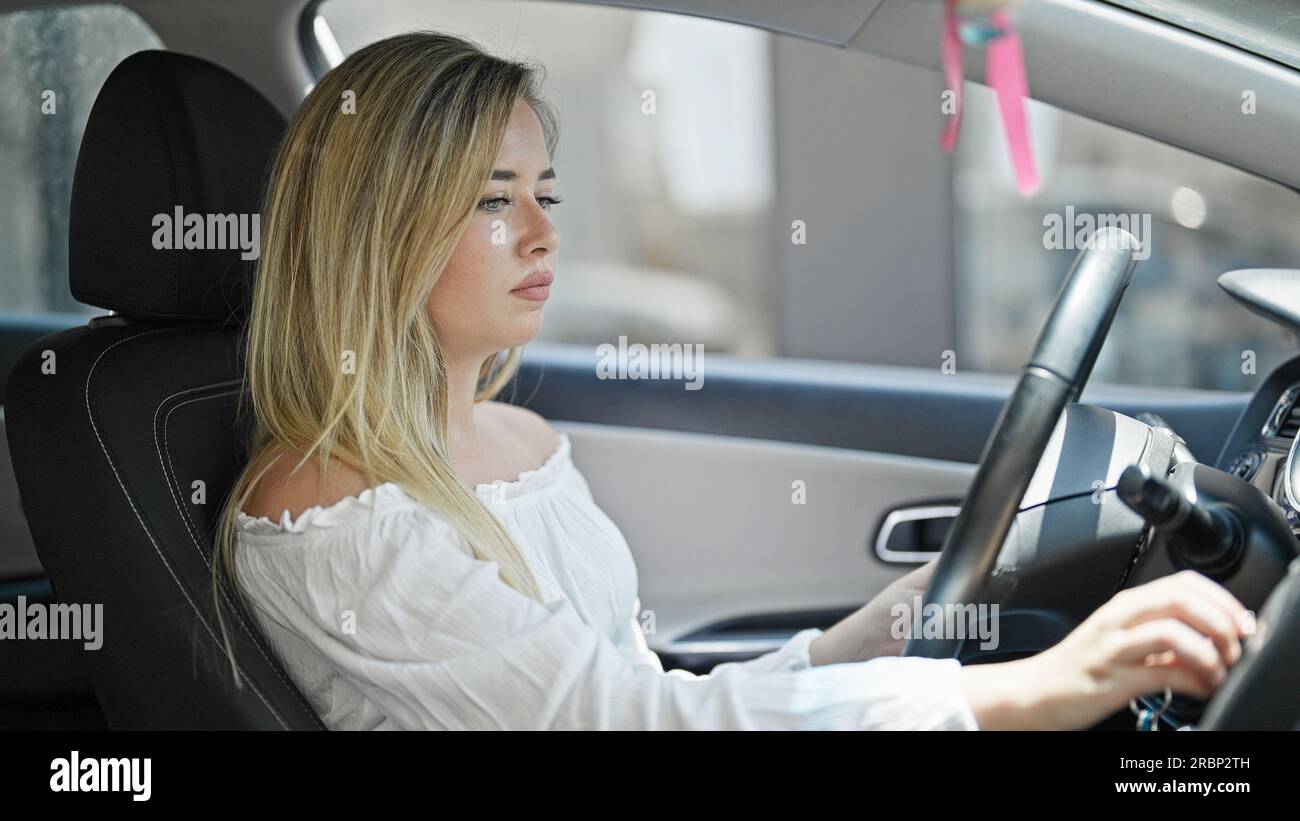 Young blonde woman driving car at street Stock Photo - Alamy