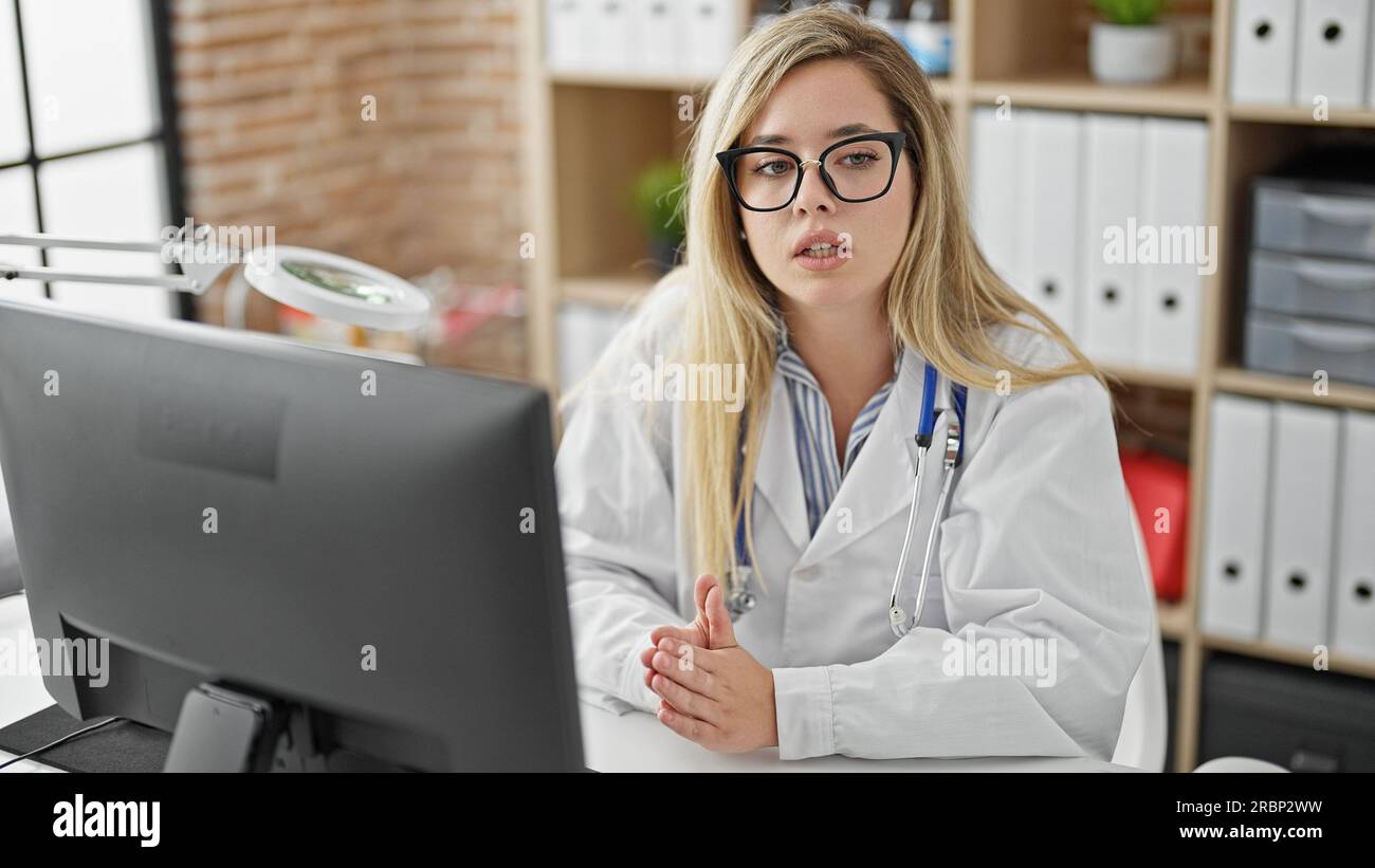 Young blonde woman doctor using computer speaking at clinic Stock Photo ...