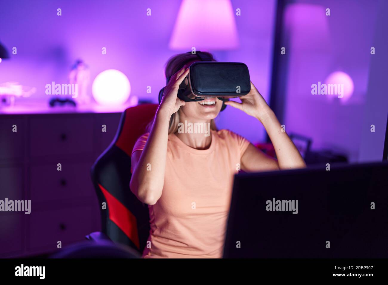 Young blonde woman streamer playing video game using virtual reality ...