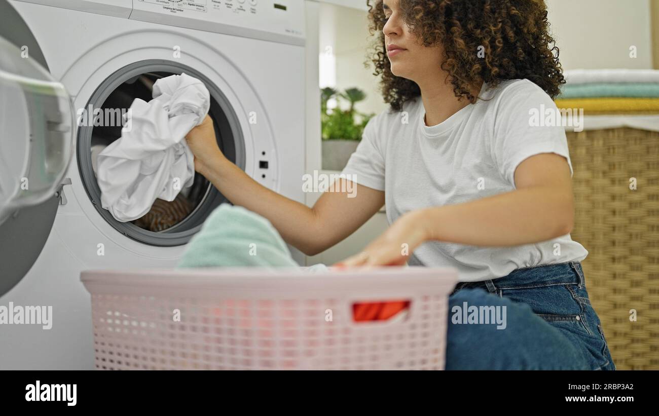 Young beautiful hispanic woman washing clothes at laundry room Stock ...