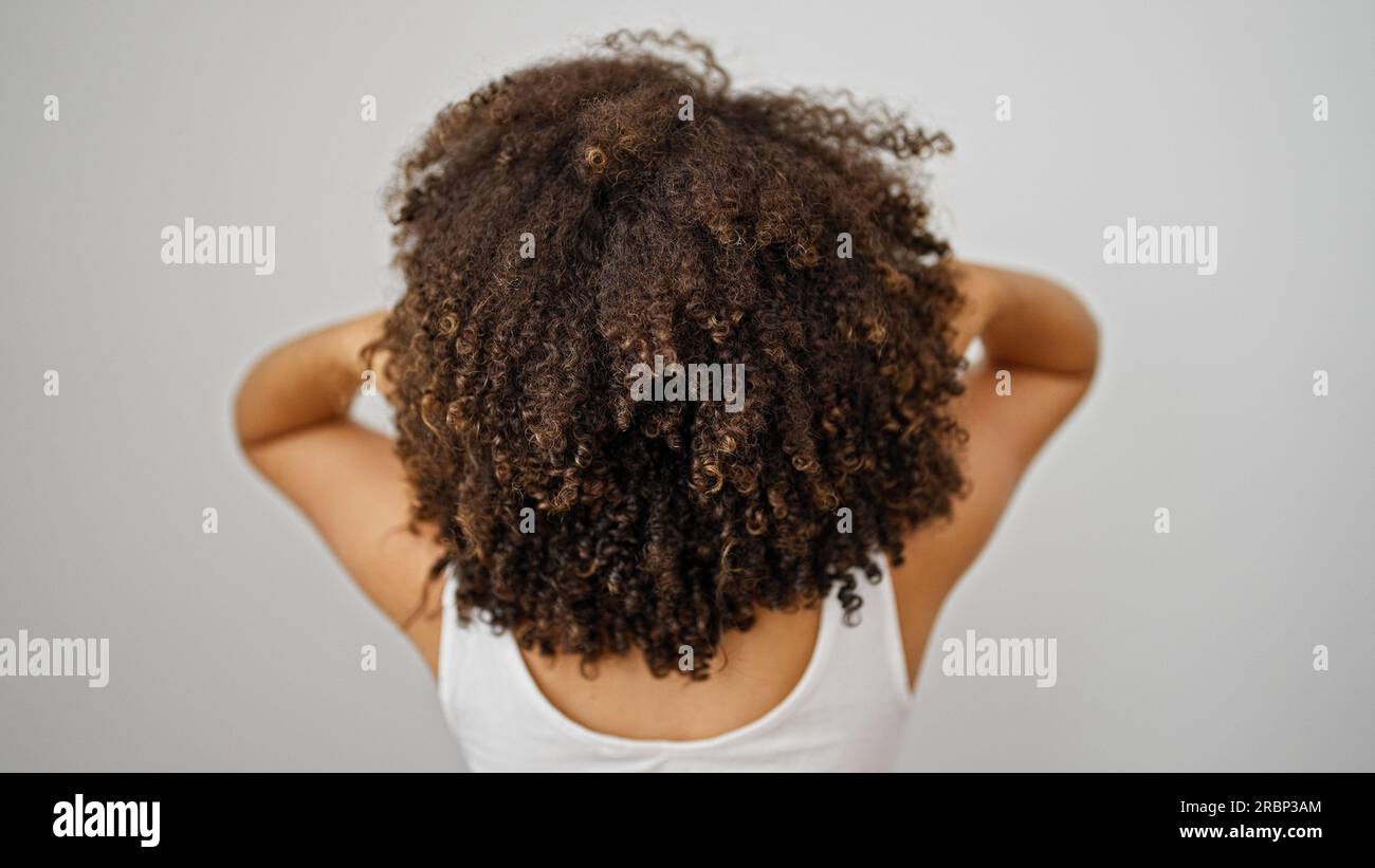 Young beautiful hispanic woman touching her hair backwards over ...