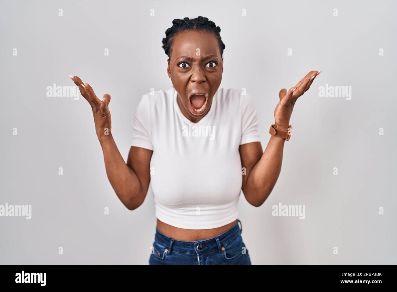 Beautiful black woman standing over isolated background crazy and mad ...