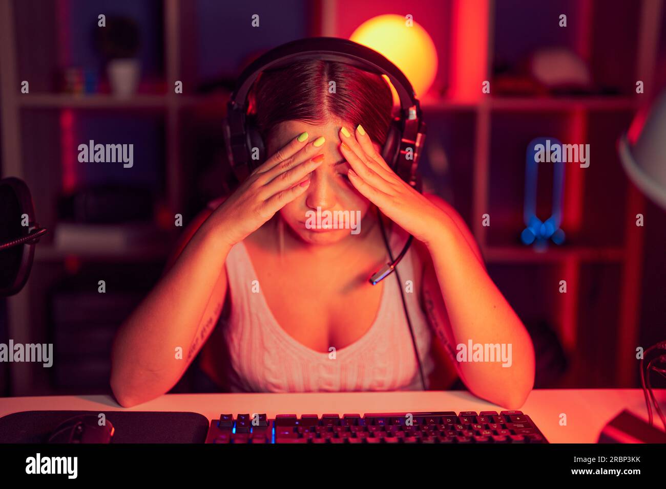 Young blonde woman playing video games wearing headphones with sad ...