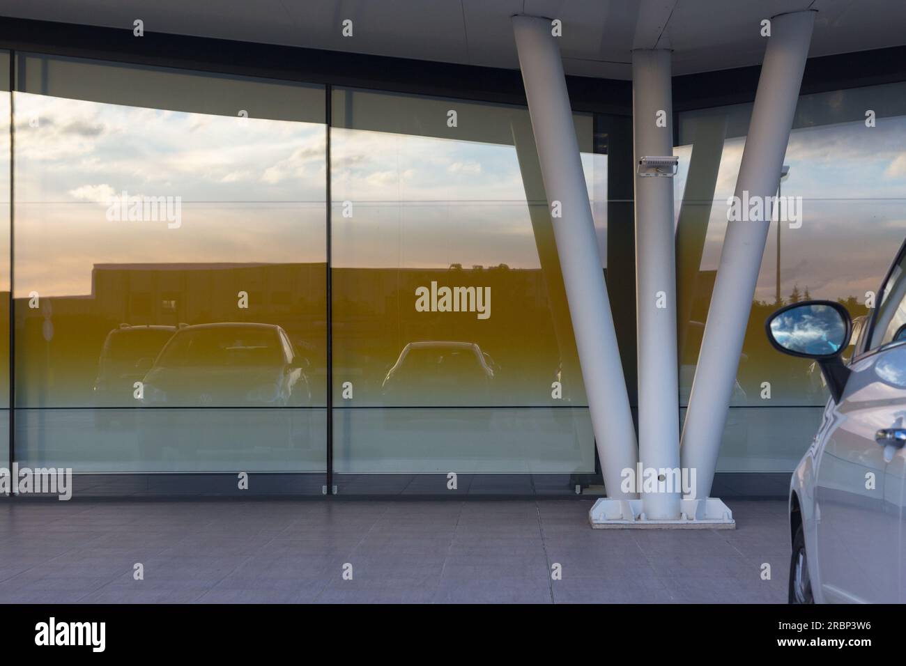 A car parked in front of a modern building with reflections of other ...