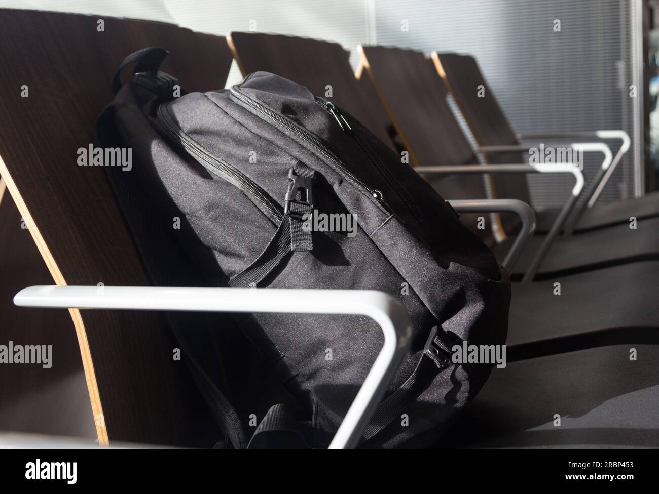 A black backpack sitting in a row of empty seats in a waiting area ...