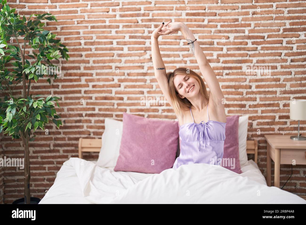 Young blonde woman waking up stretching arms at bedroom Stock Photo - Alamy