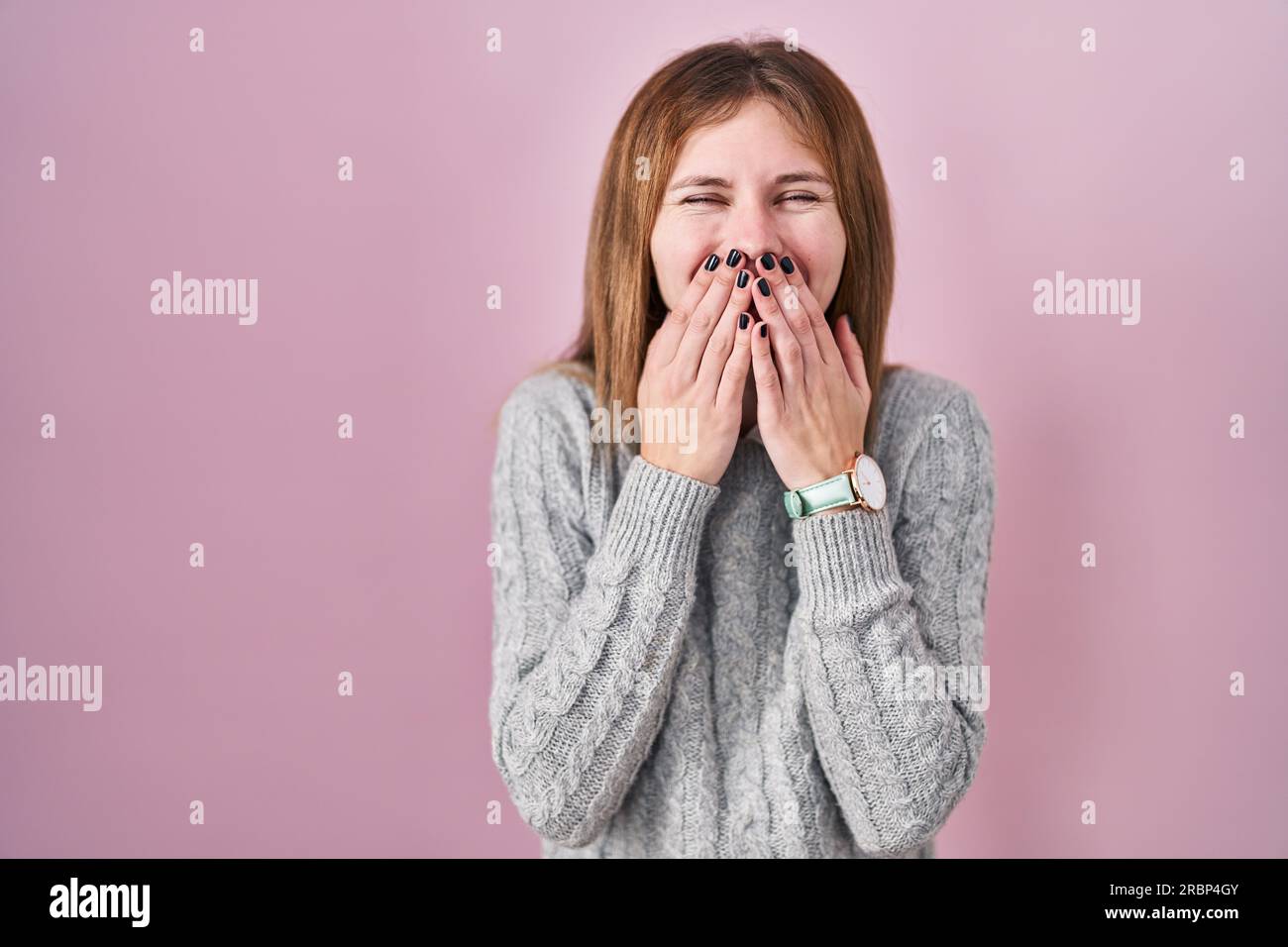 Beautiful woman standing over pink background laughing and embarrassed ...