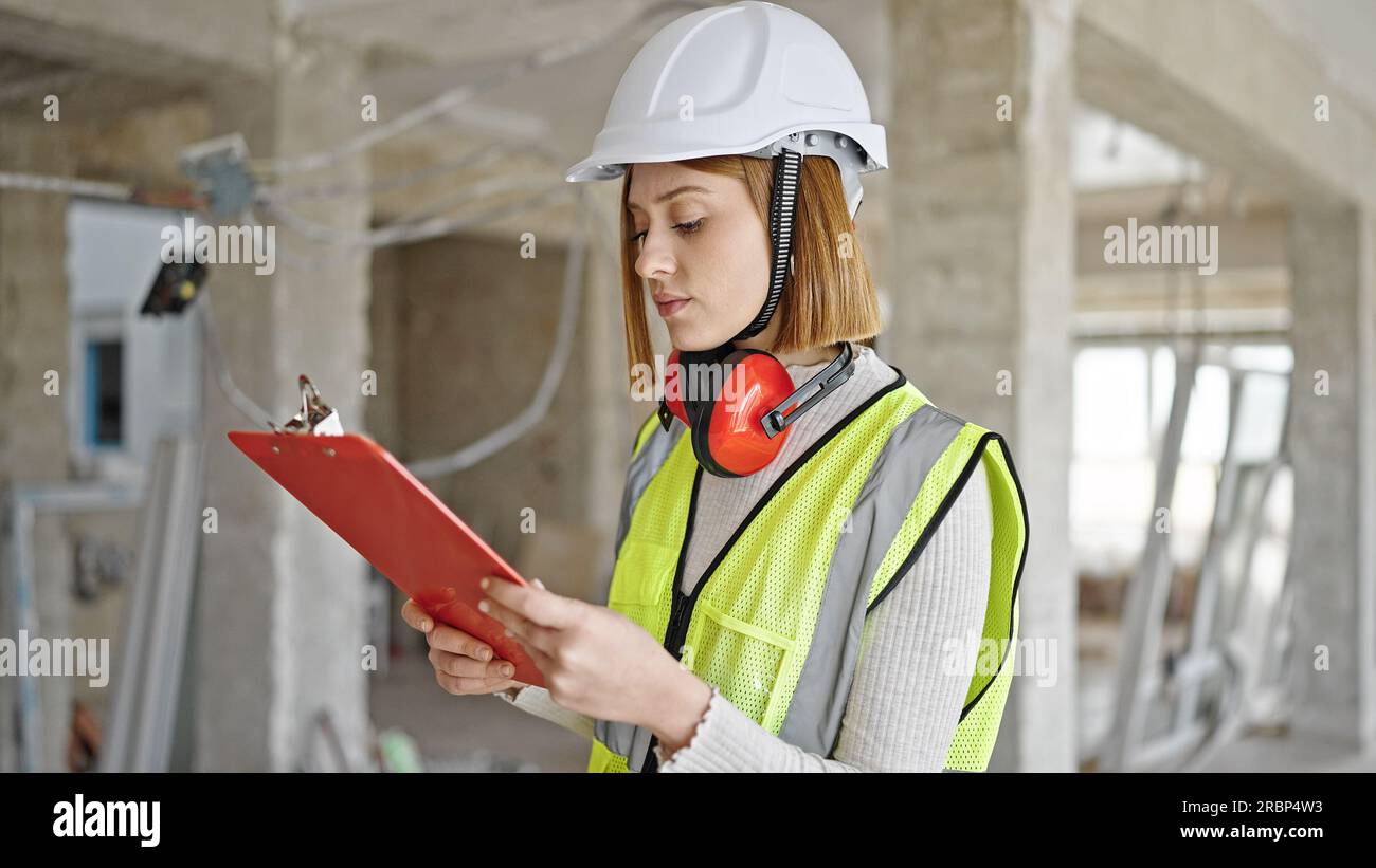 Young blonde woman architect reading document at construction site ...