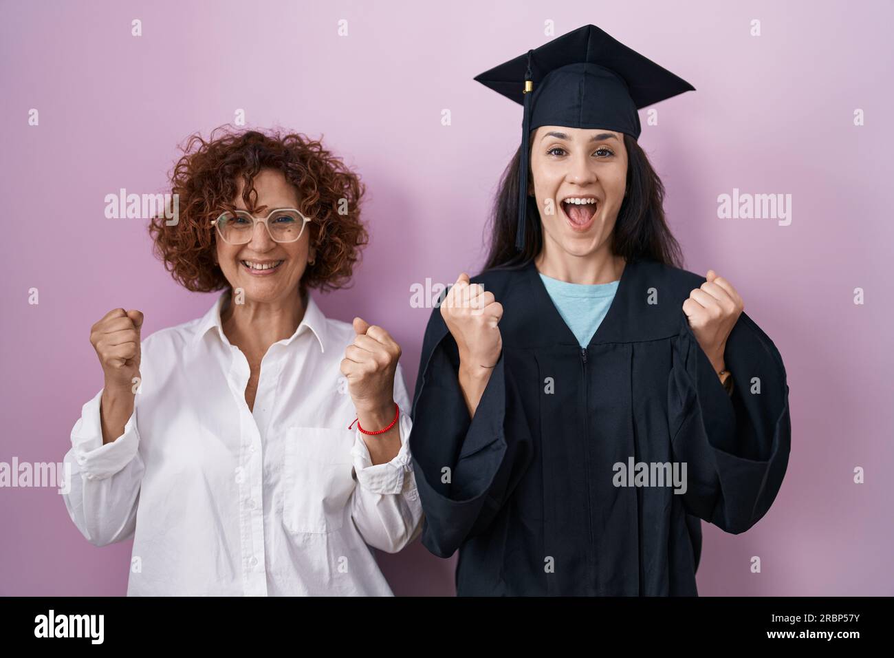 Hispanic mother and daughter wearing graduation cap and ceremony robe ...