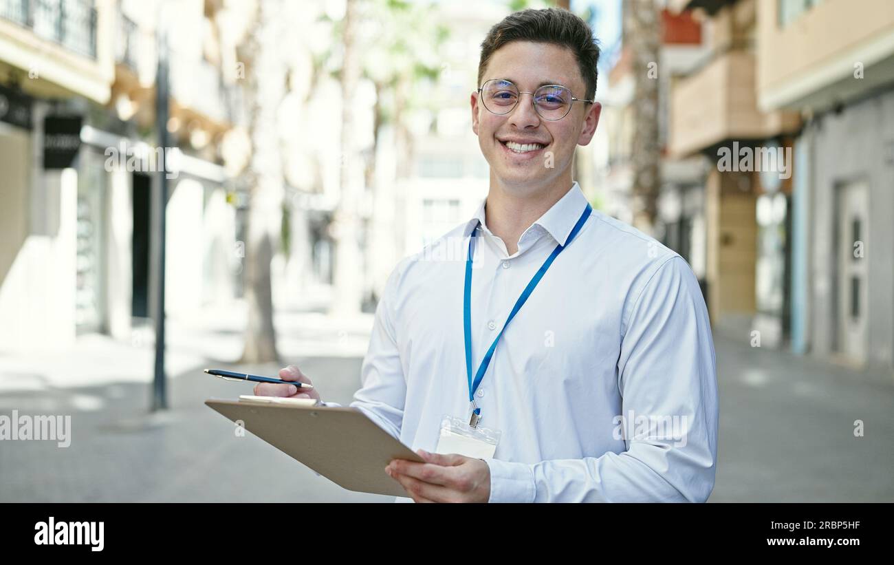 Young hispanic man having survey interview writing on clipboard at ...