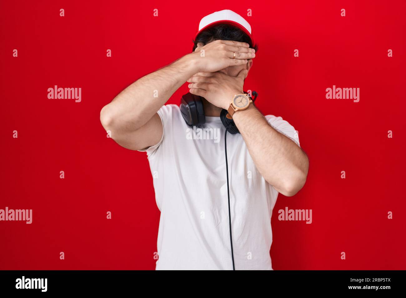 Hispanic man with beard wearing gamer hat and headphones covering eyes ...