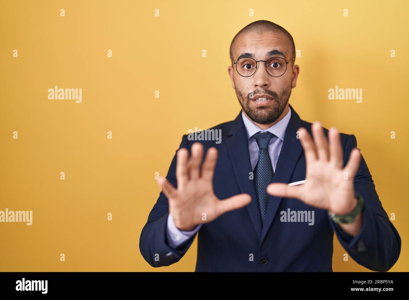 Hispanic man with beard wearing suit and tie afraid and terrified with ...