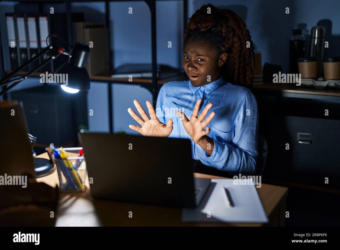 African woman working at the office at night afraid and terrified with ...