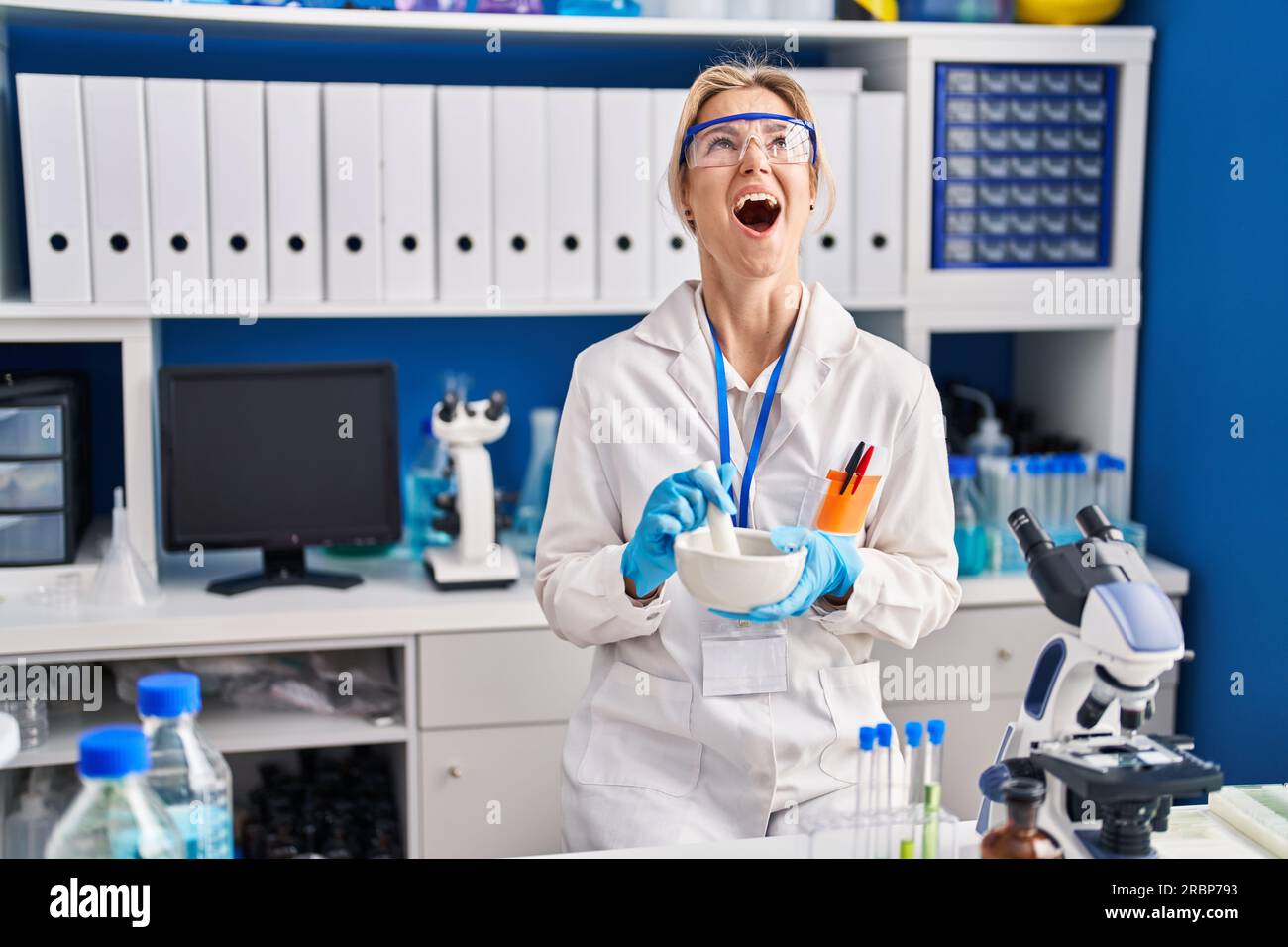 Young caucasian woman working at scientist laboratory angry and mad ...