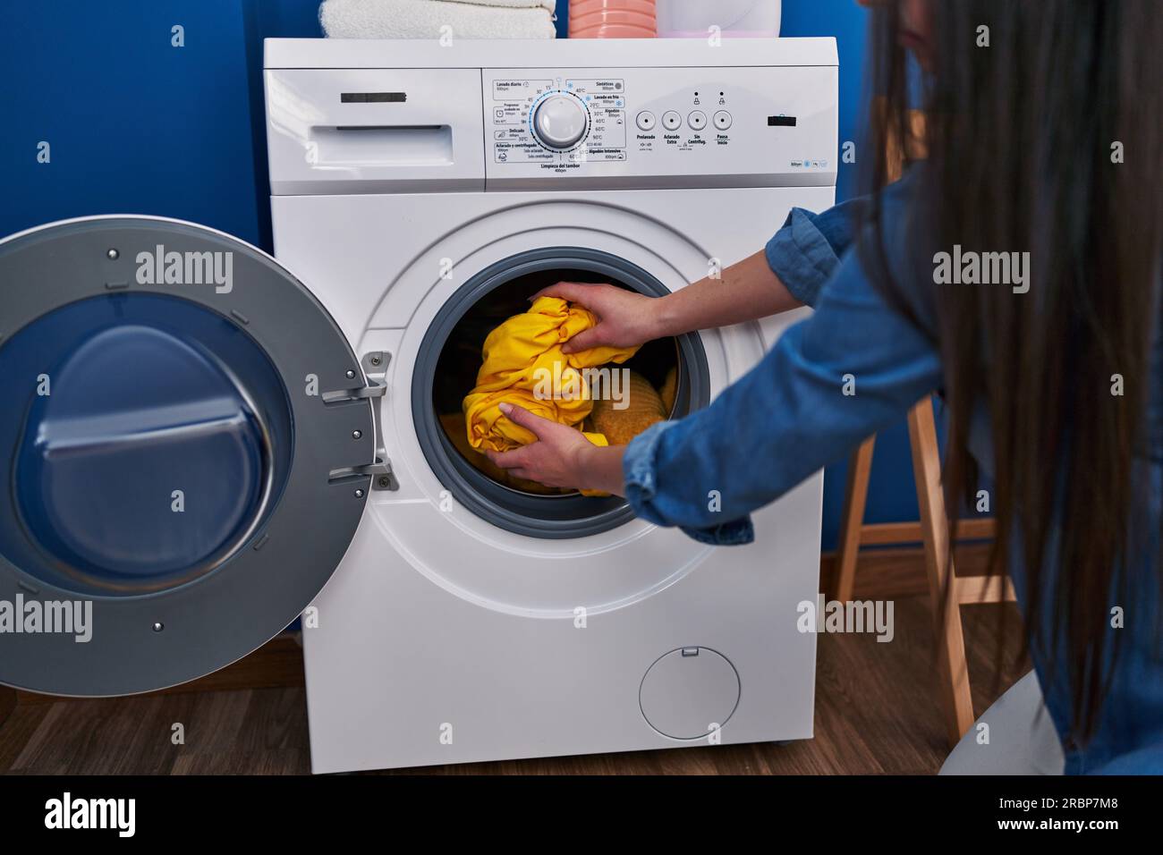 Young beautiful hispanic woman washing clothes at laundry room Stock ...