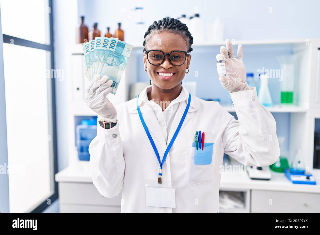 African woman with braids working at scientist laboratory holding money ...