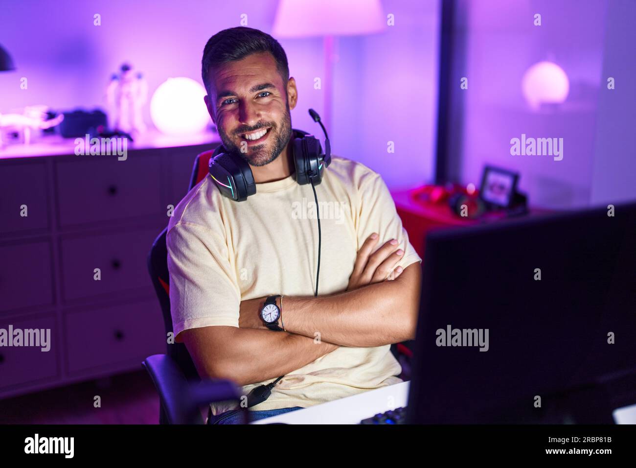 Young hispanic man streamer smiling confident sitting with arms crossed ...