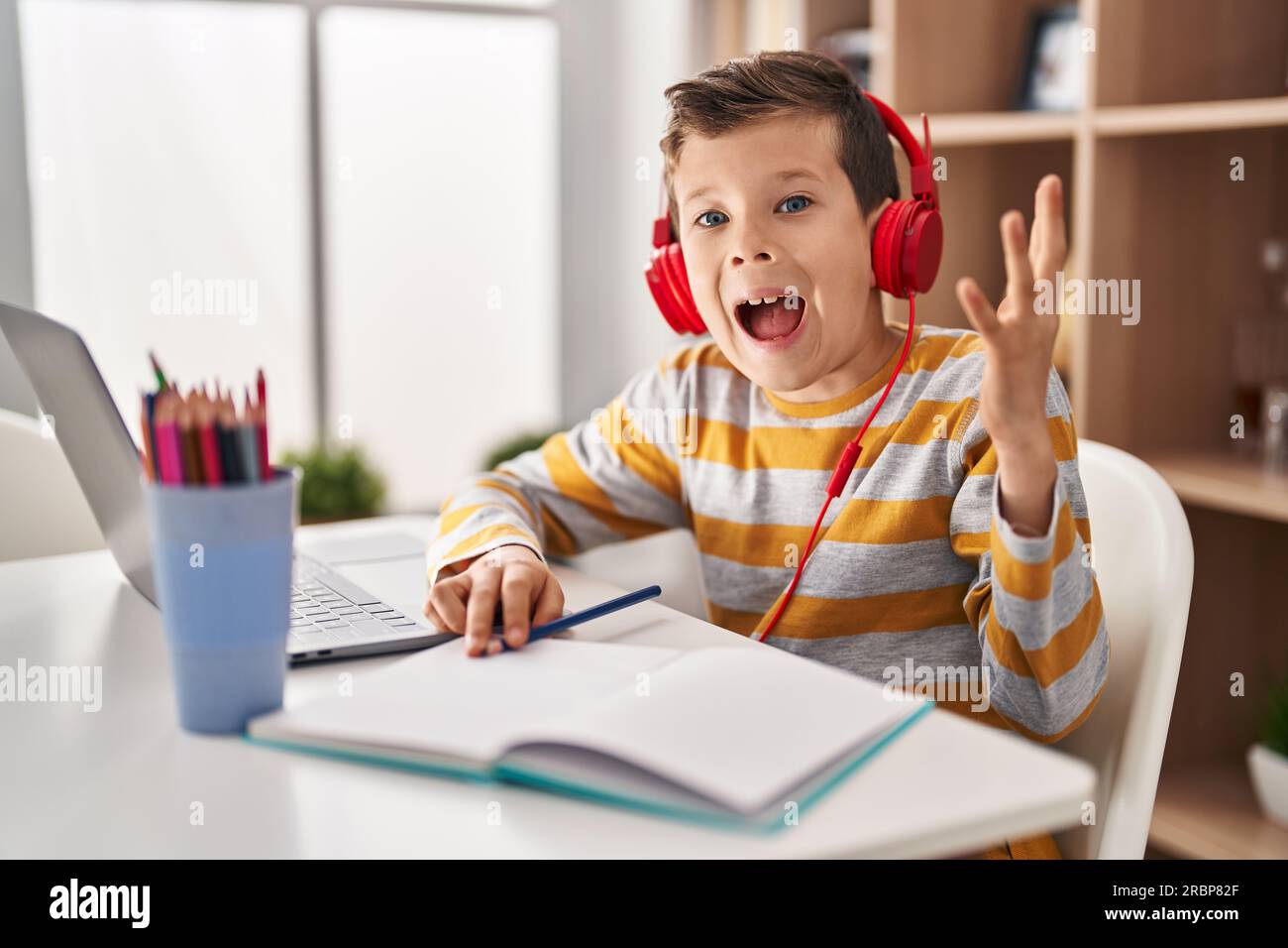 Young caucasian kid doing homework at home celebrating victory with ...