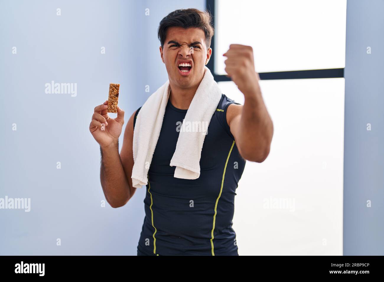 Hispanic man eating protein bar as healthy energy snack annoyed and ...