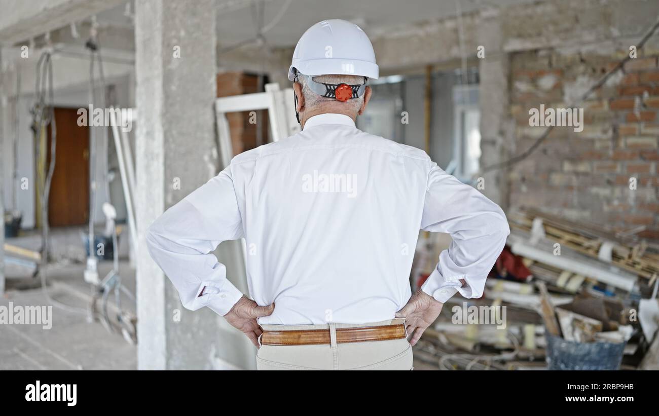 Senior grey-haired man architect standing backwards at construction ...