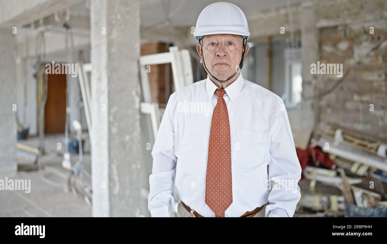 Senior grey-haired man architect standing with relaxed expression at ...
