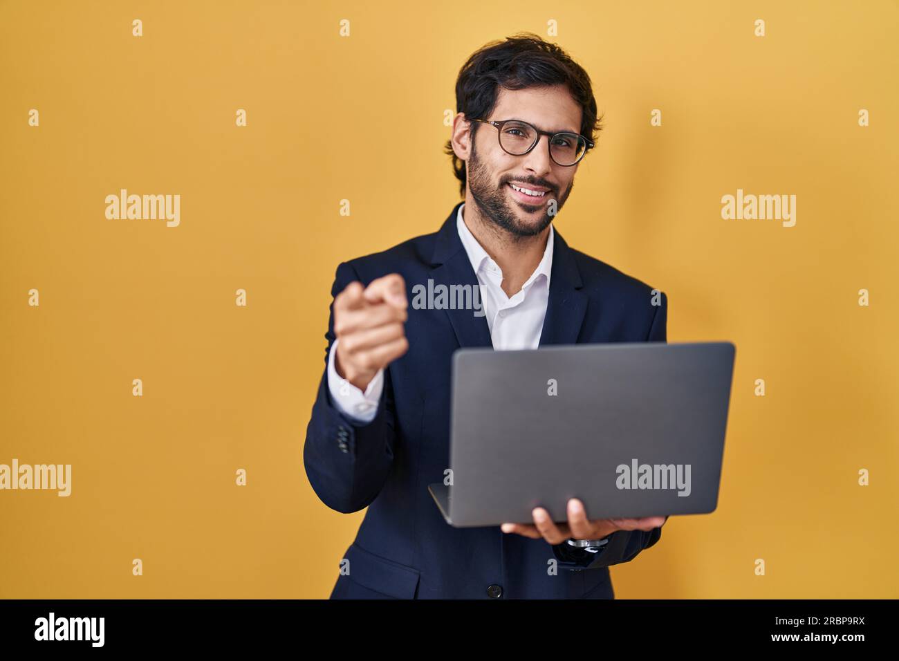 Handsome latin man working using computer laptop pointing fingers to ...