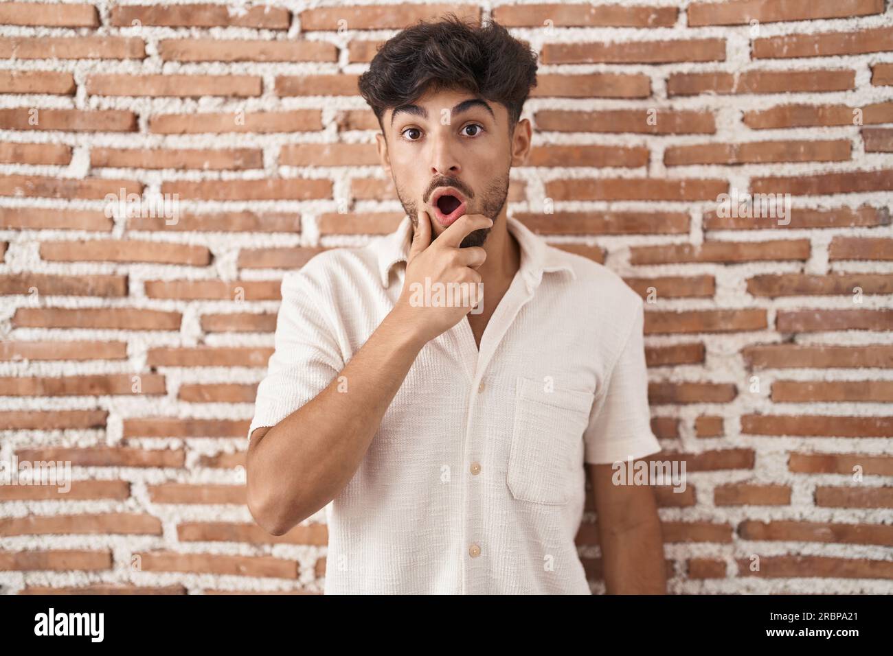 Arab man with beard standing over bricks wall background looking ...