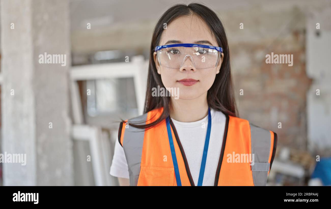 Young chinese woman builder standing with relaxed expression at ...